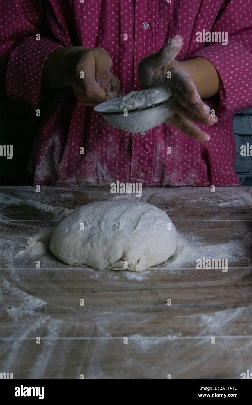 The woman sprinkles flour dough from the fullness for sifting flour ...