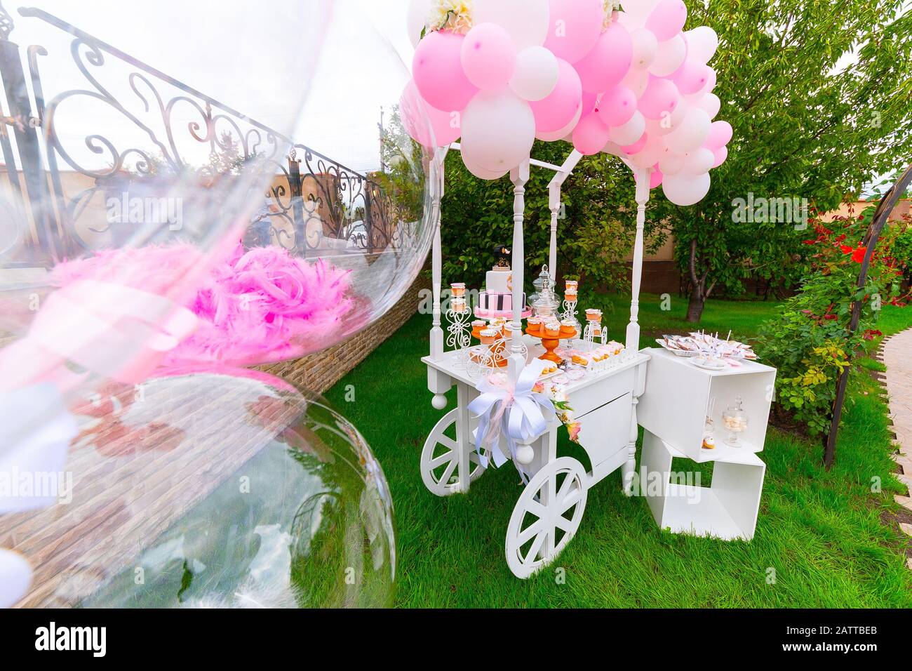 Candy Bar. White wooden trolley with sweets decorated with balloons on ...