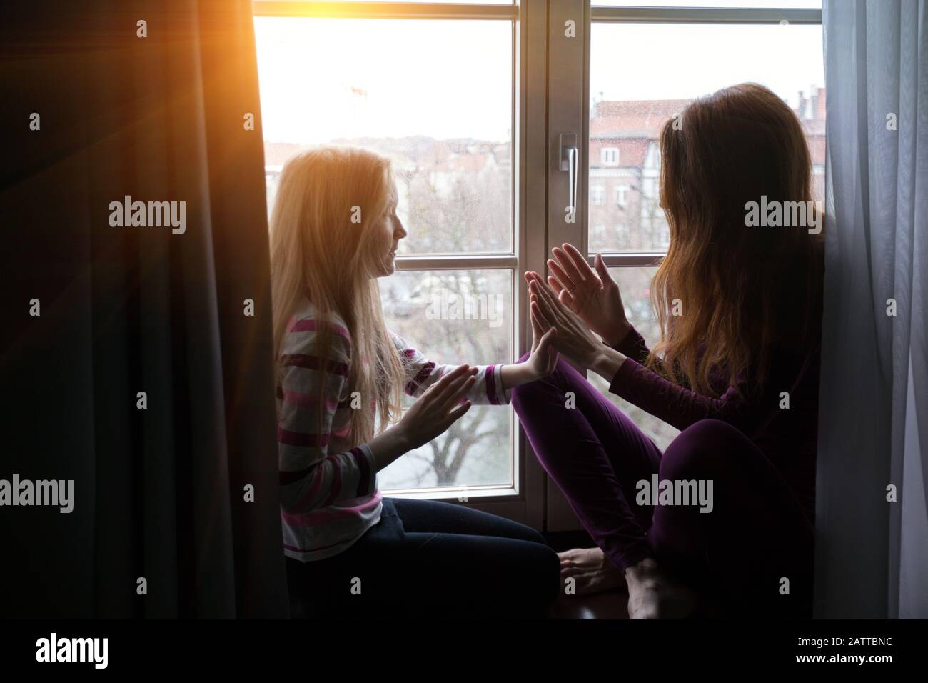 girl sitting on a windowsill. mom and daughter play a game Stock Photo ...