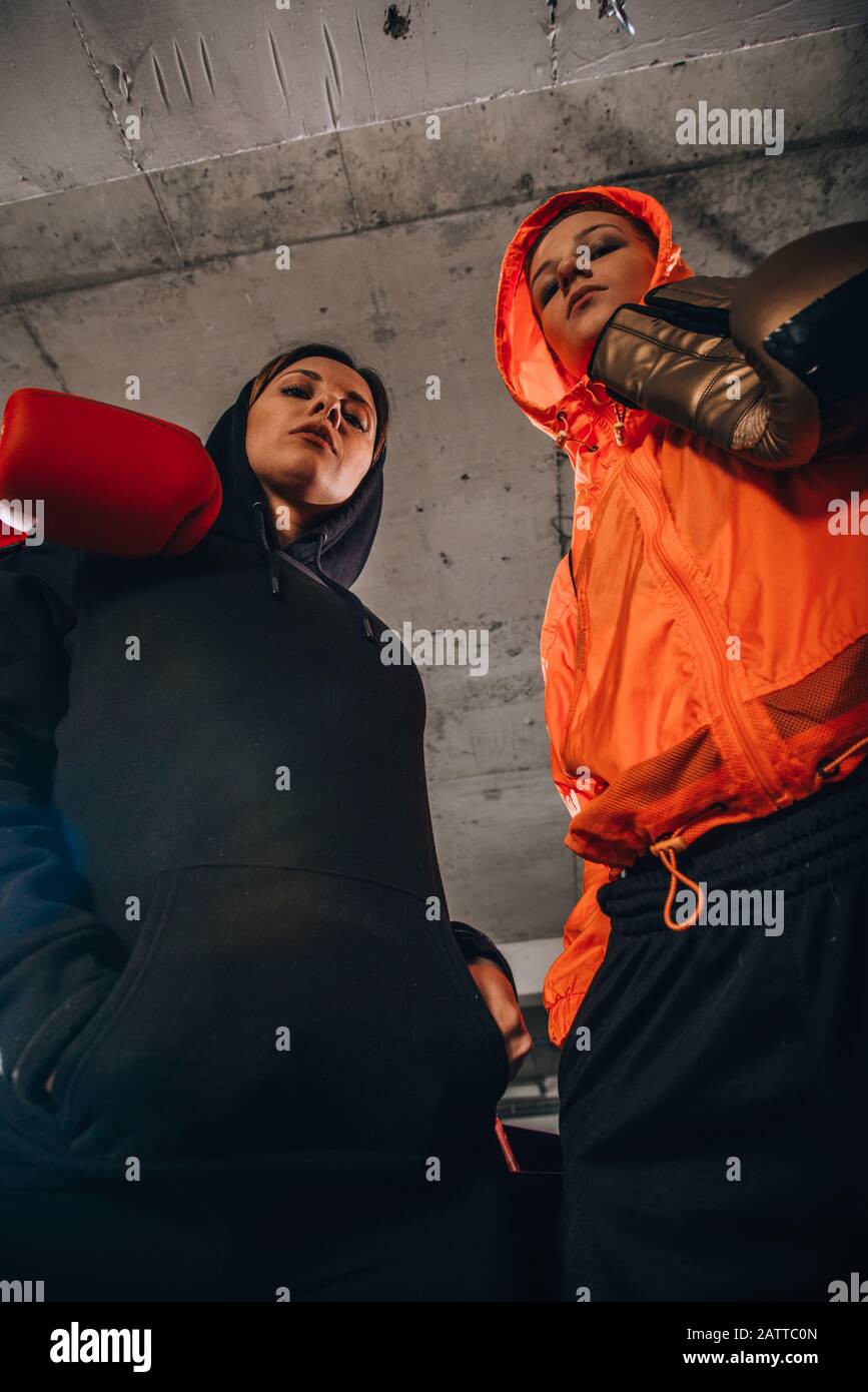Below view of two female boxer friends standing in a garage with boxing ...