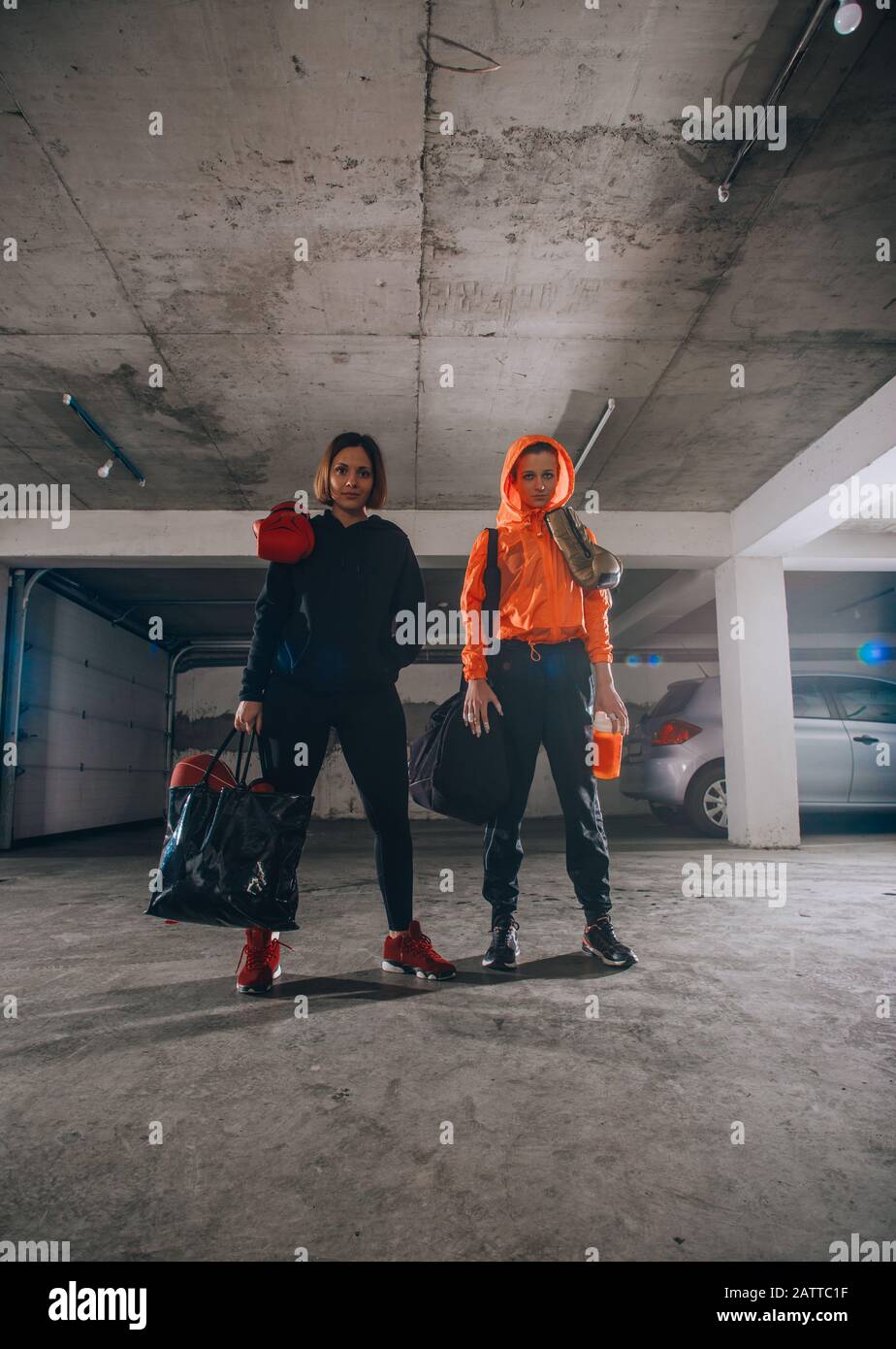 Two female boxer friends standing in a garage with boxing equipment ...