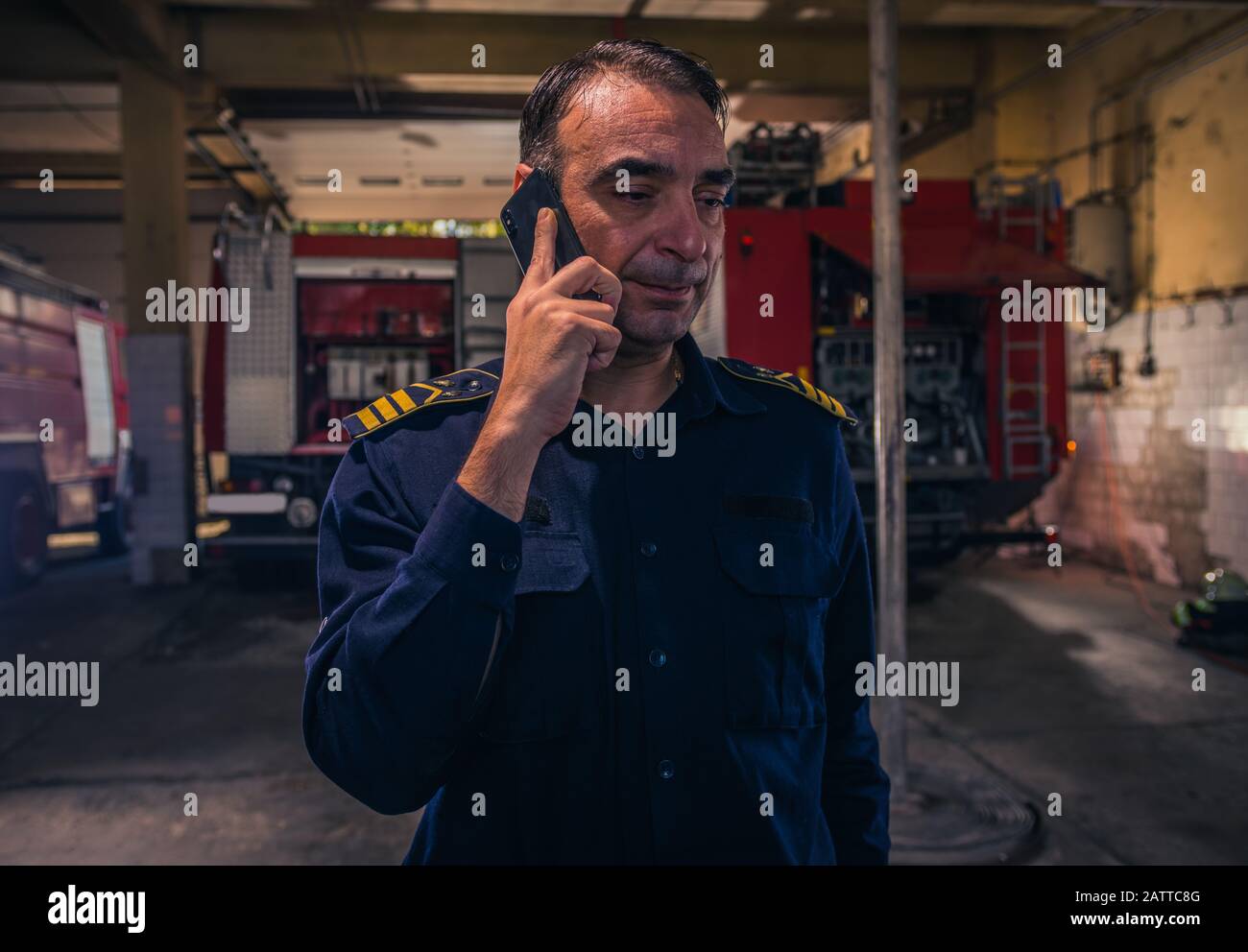 Portrait of fireman talking on the phone while standing inside the fire ...