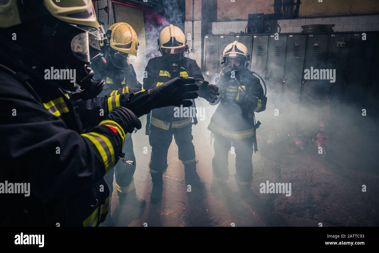 Firemen in uniform wearing gloves and gas masks inside the fire ...