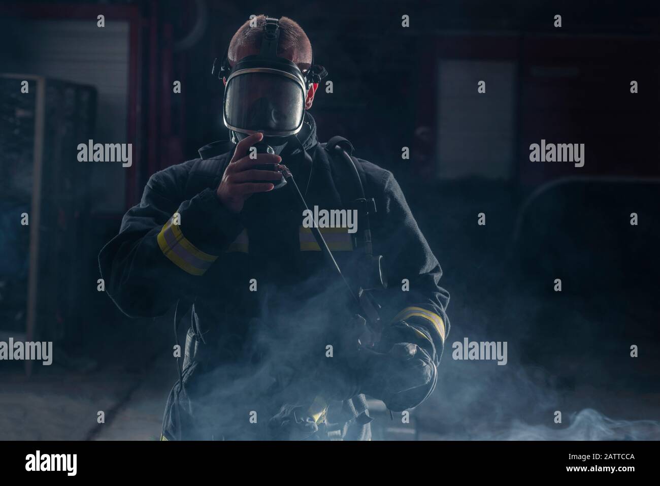 Portrait of a fireman wearing firefighter turnouts and helmet. Dark ...