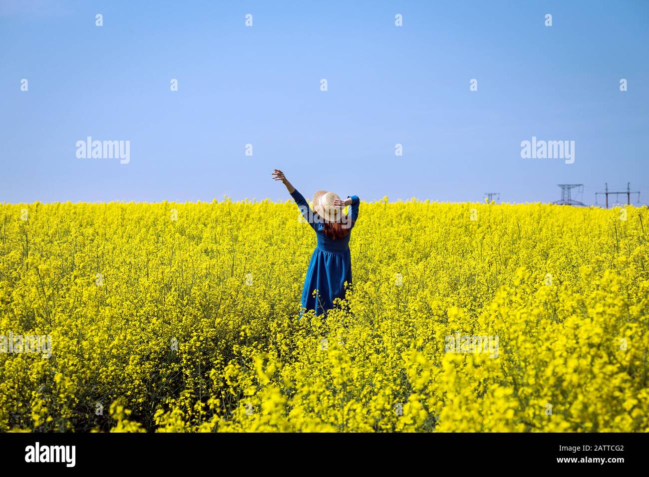 Happy girl in a hat walking in amazing field of yellow rapeseed in the ...