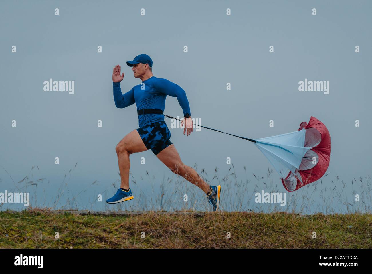 Trail running man with resistance parachute on path exercising Stock ...