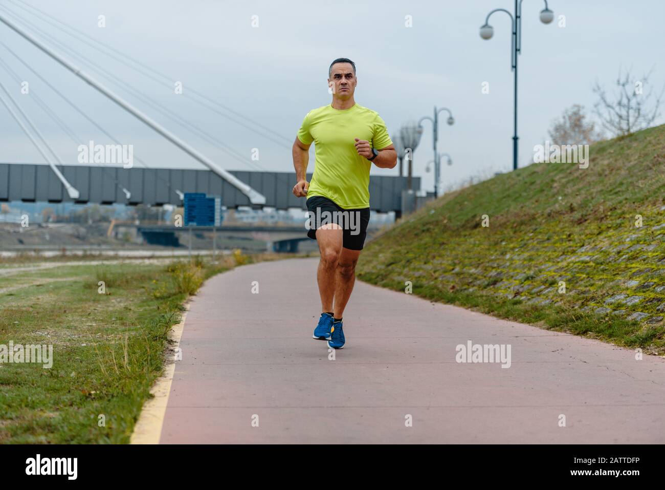 Older well built man in activewear stretching out his legs before ...