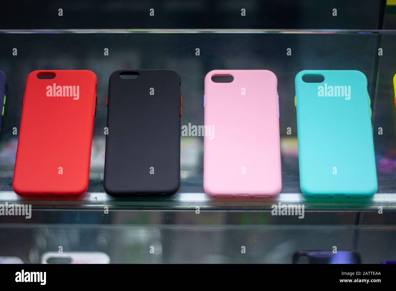 3 different color phone cases in the shop window.. There is a glass in ...