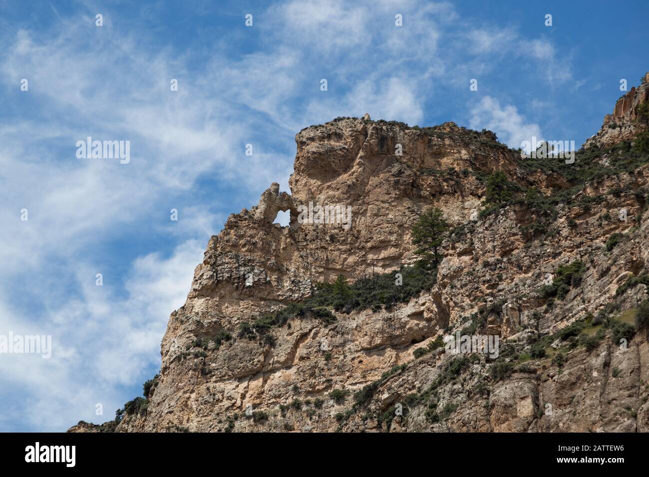 A rock arch formed high up on a canyon wall from eroding sedimentary ...