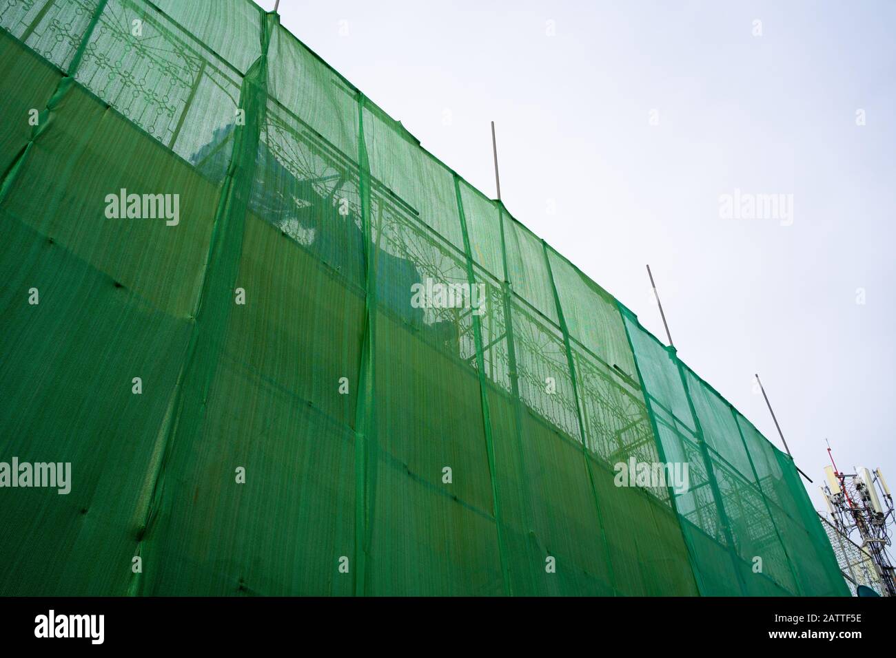 Construction building wrapped with green fabric for safety reasons ...