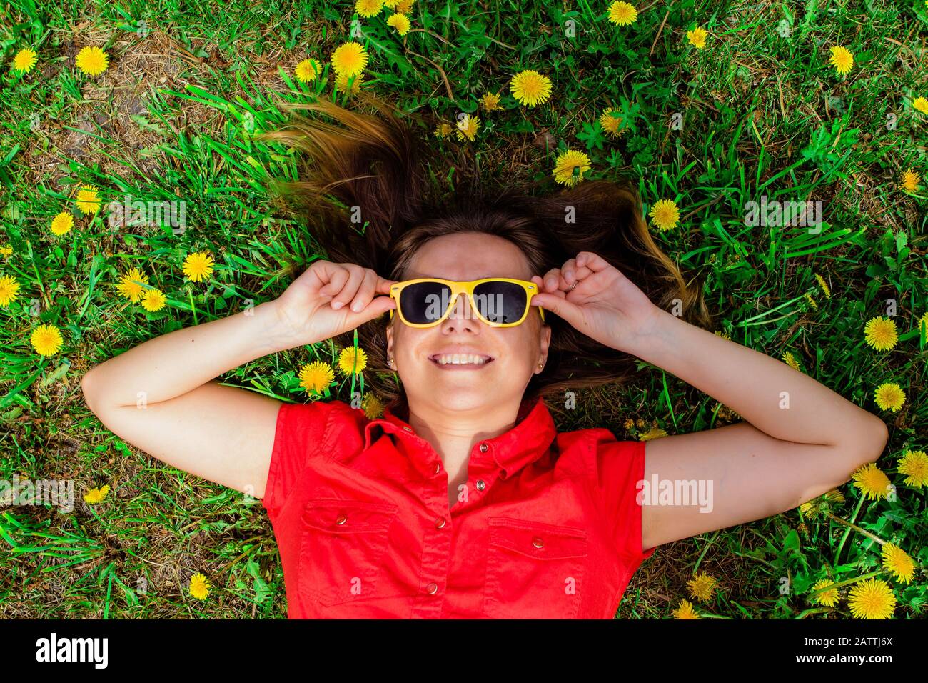 Woman In Red Shirt And Yellow Sunglasses Lying On The Field Of