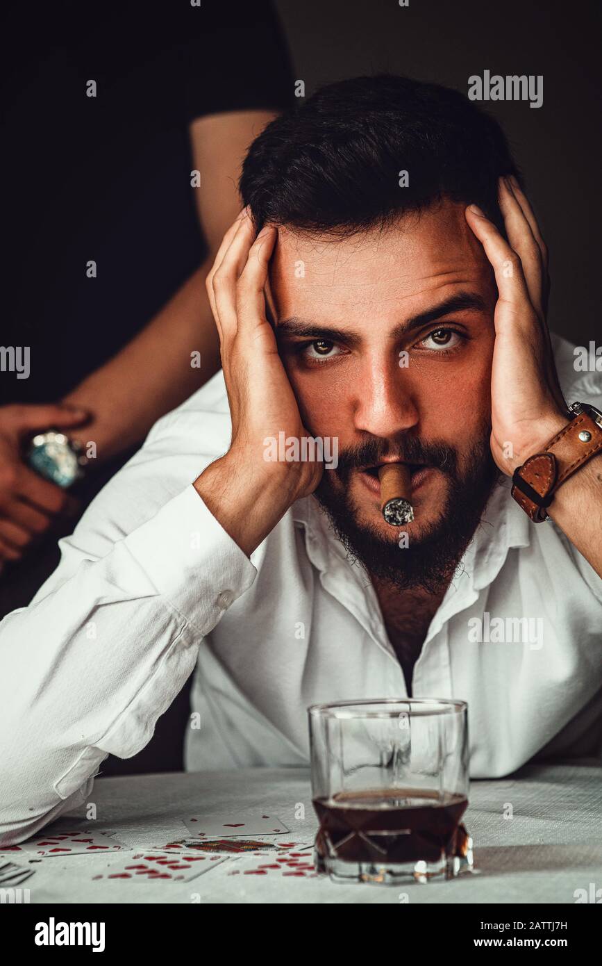 The young gambler man takes serious looks at the camera at the gambling ...