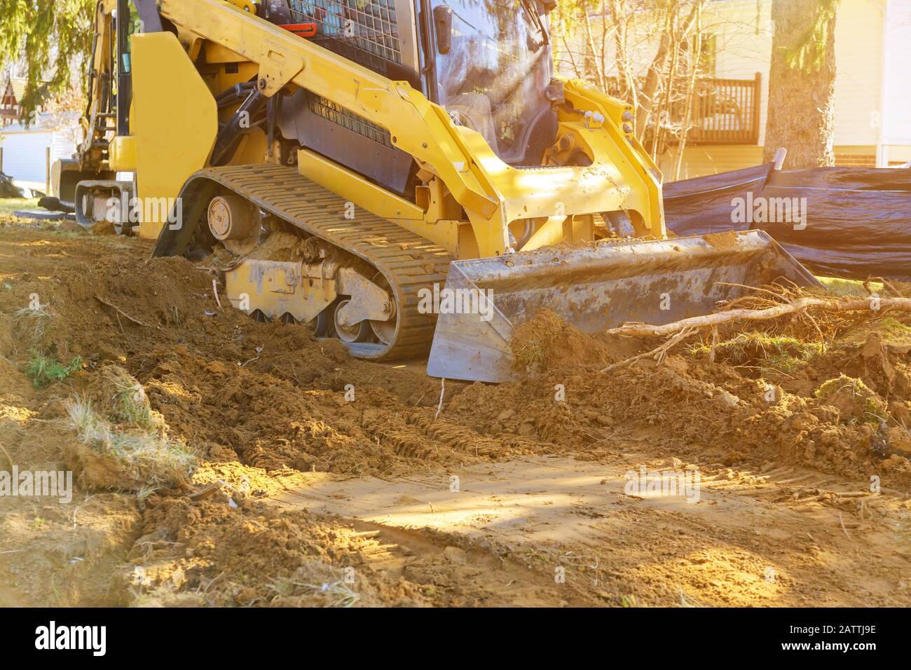 Mini bulldozer working with earth while doing landscaping works on ...