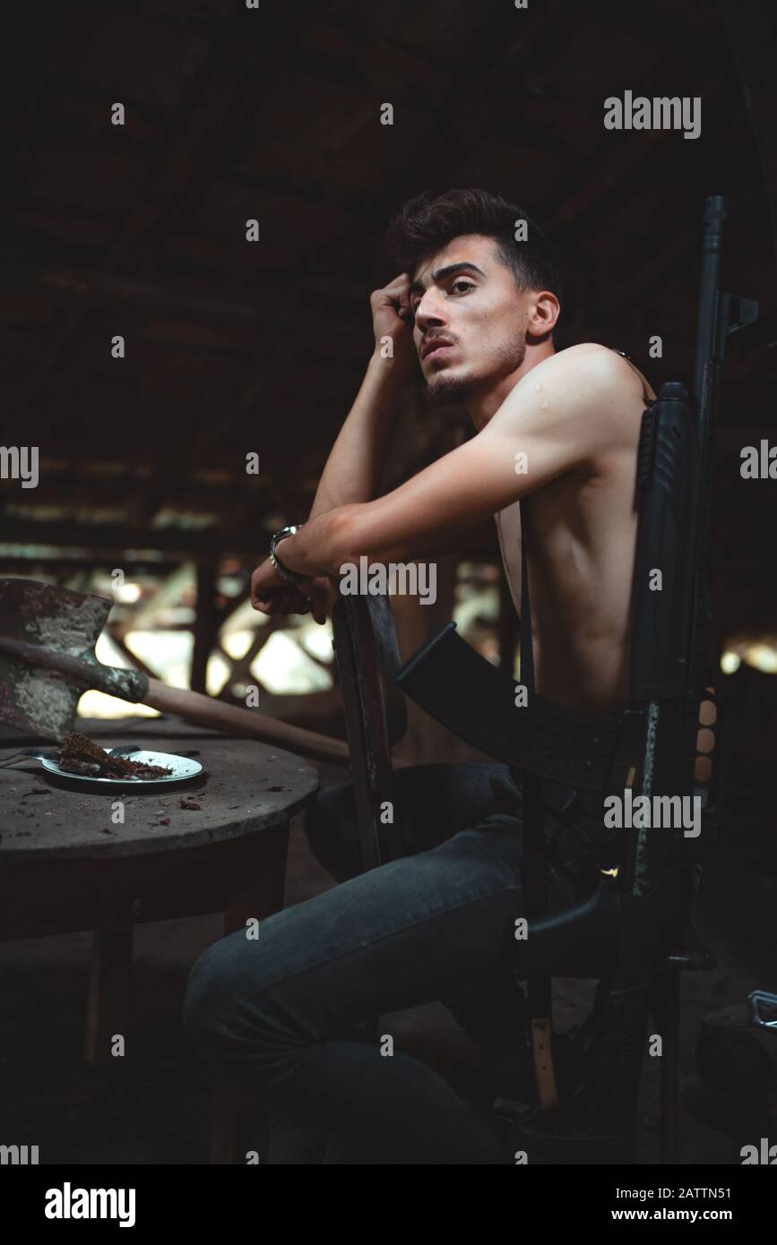The gang member sitting at the bare table with a gun next to him. Mafia ...