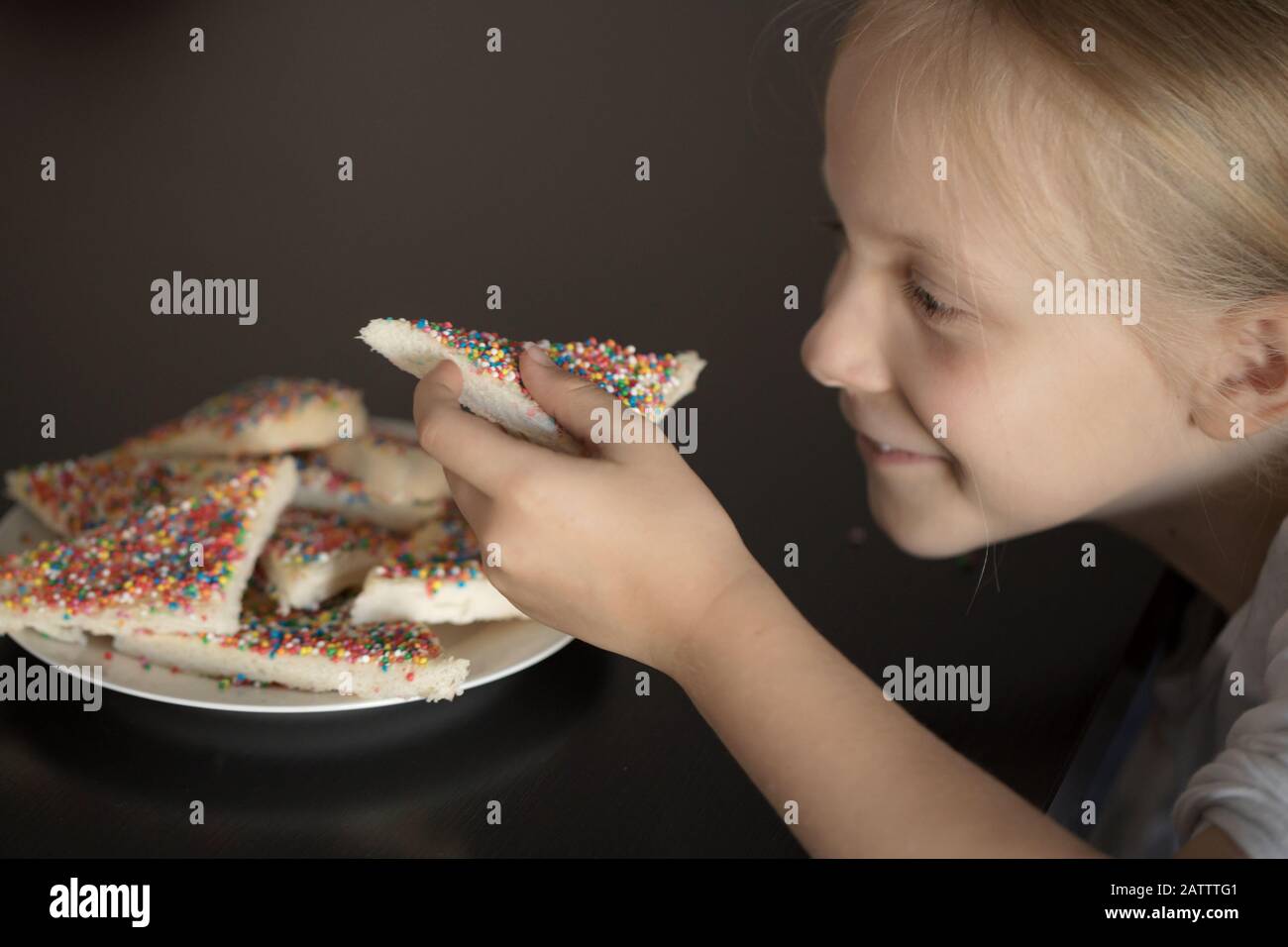 Young girl eating fairy bread Stock Photo - Alamy