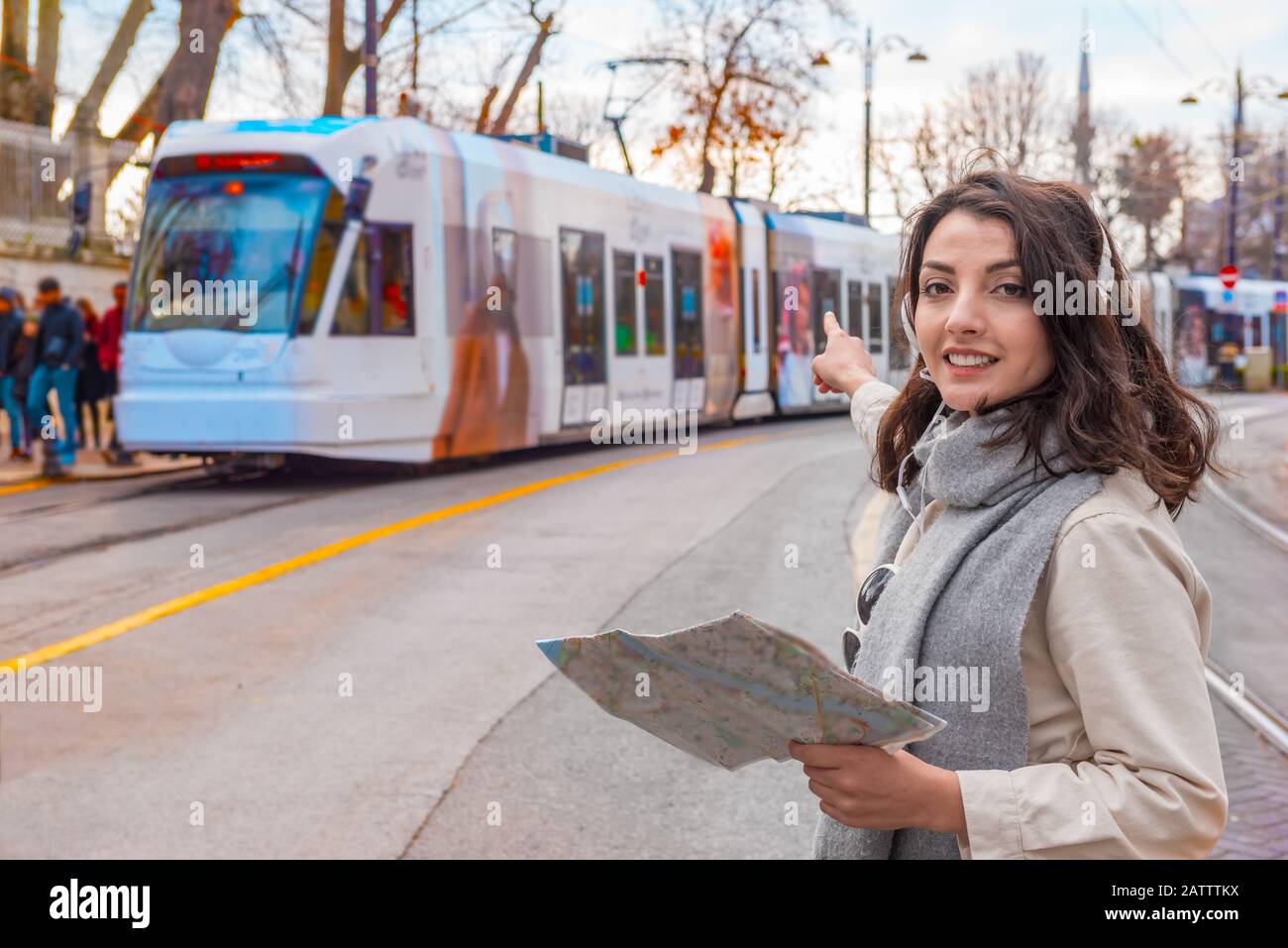 Beautiful young girl in fashionable clothes with map Tramway vehicle in ...