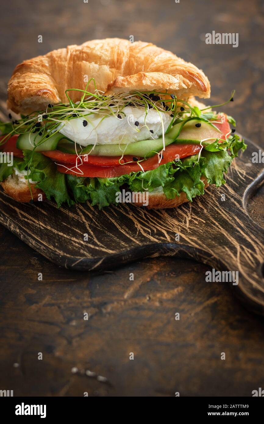 Croissant with red fish, poached egg and microgreens. Sandwich in a ...
