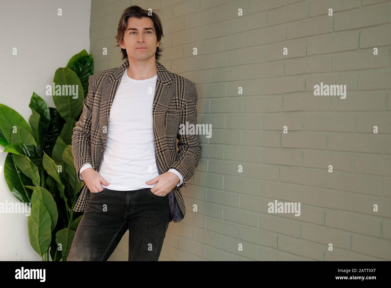 Tall handsome man standing next to grey wall Stock Photo - Alamy