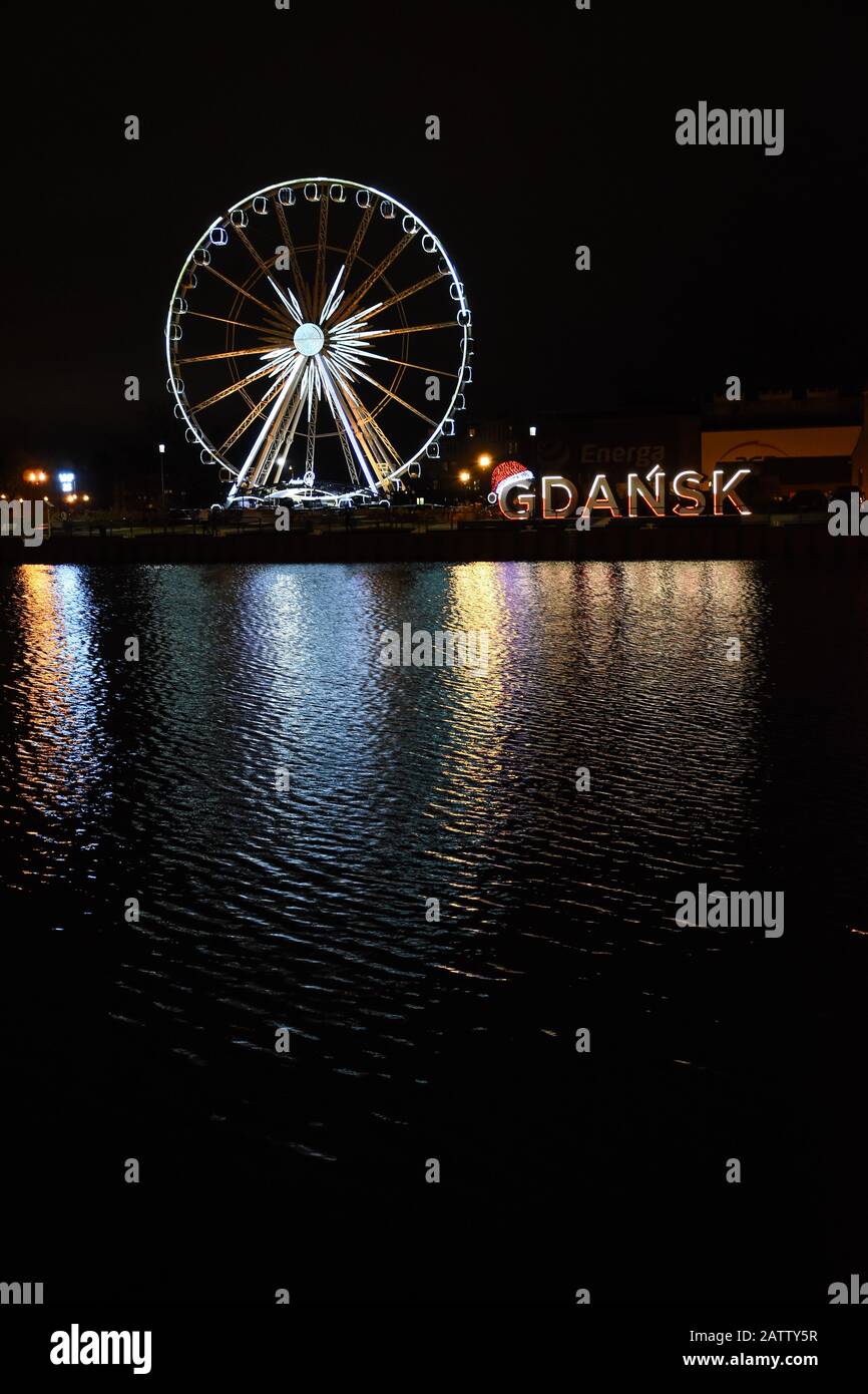 view of the city at night with lights on the water, ferris wheel Stock ...