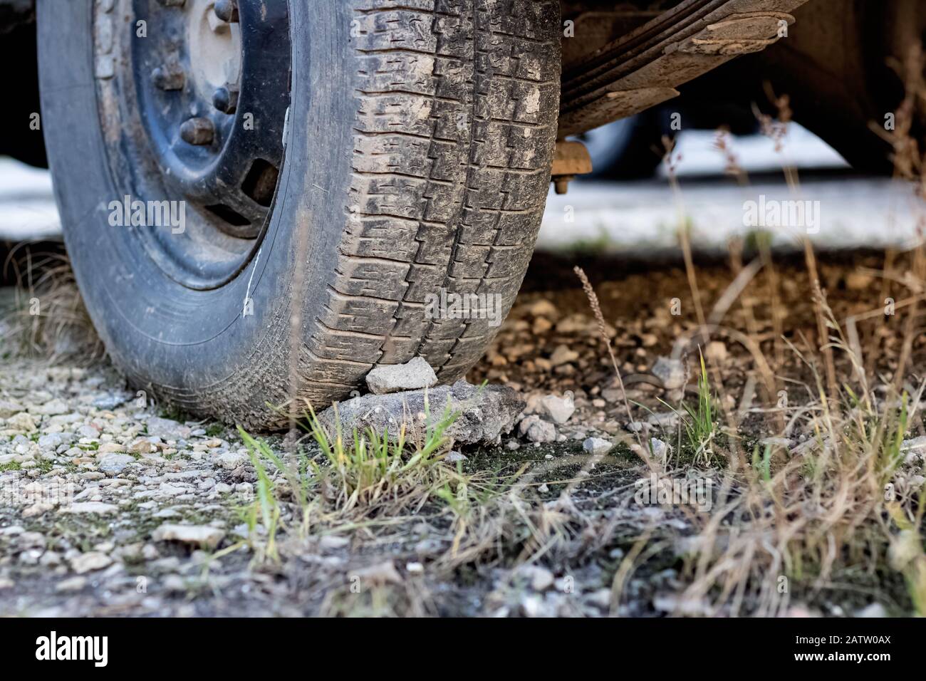 Stone under a car wheel in the grass Stock Photo - Alamy