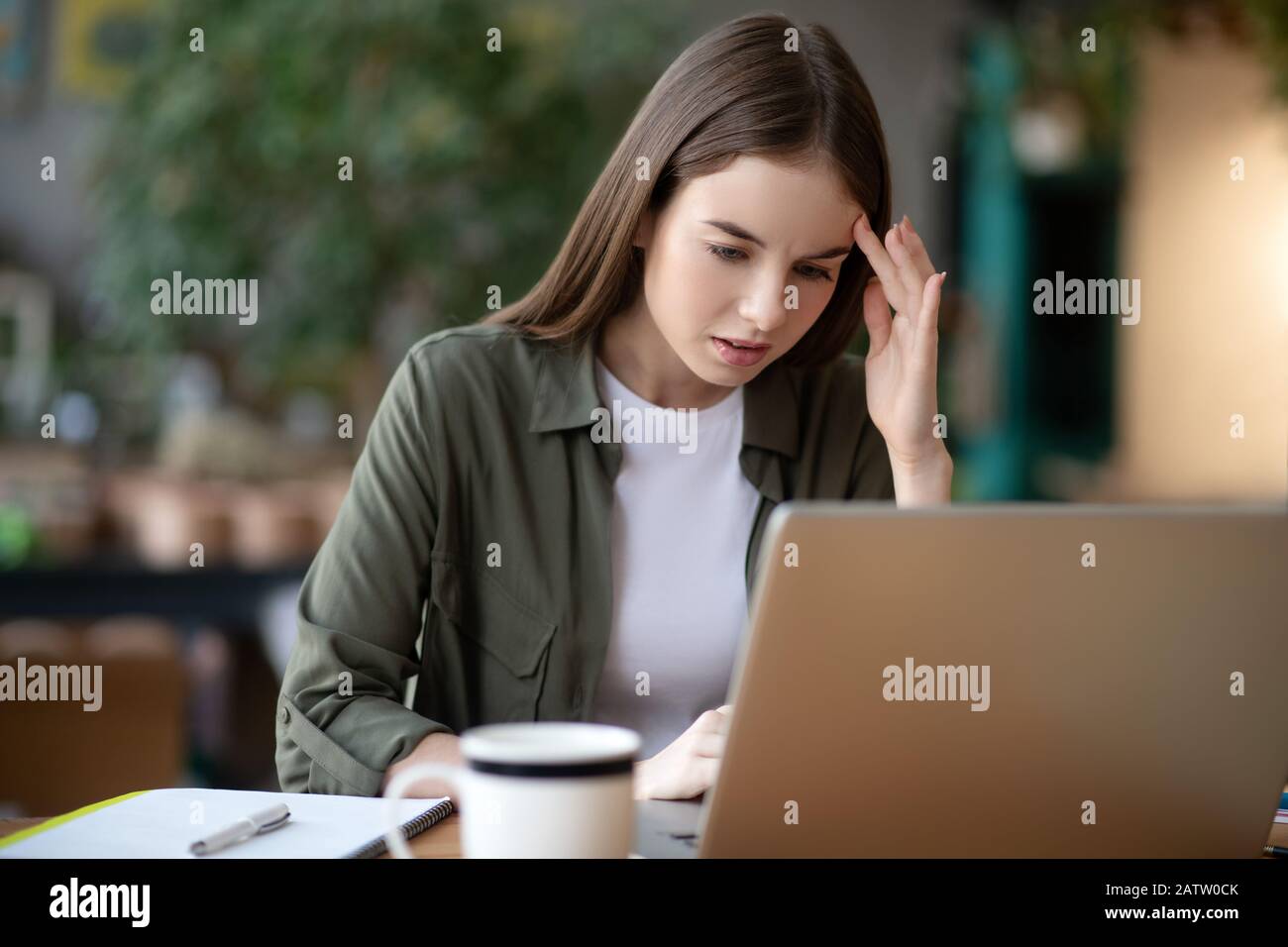 Headache. Sad girl with beautiful long hair working at a laptop in the ...