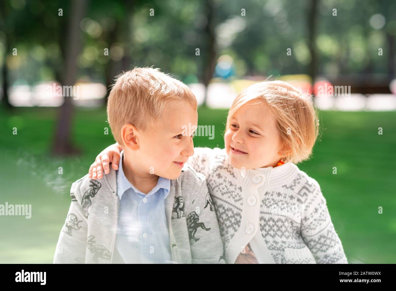 Two happy kids boy and a girl smiling and hugging together in the park ...