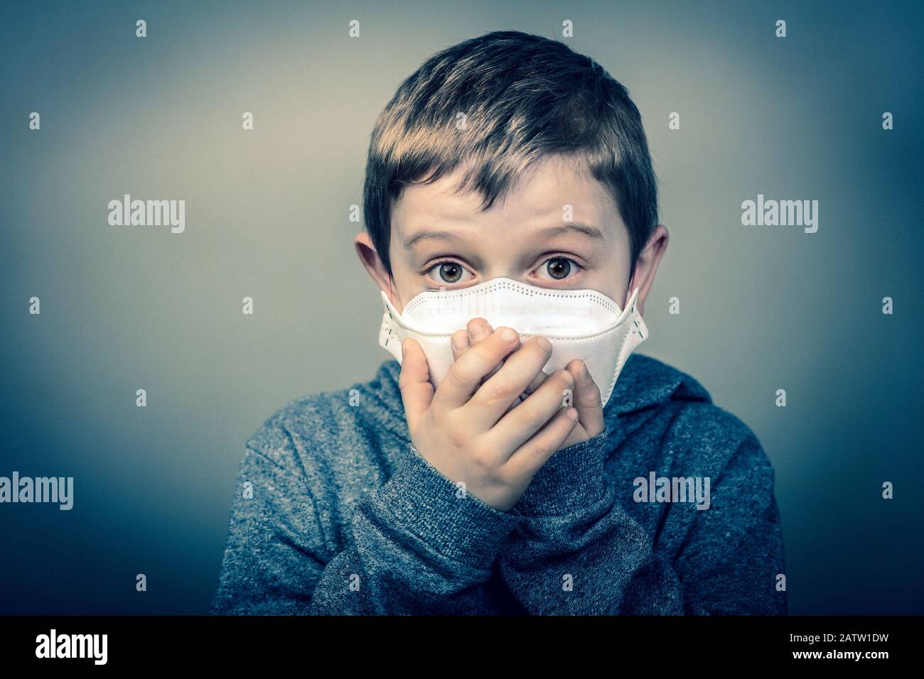 child with face mask wraps his hands over his mouth. virus prevention ...