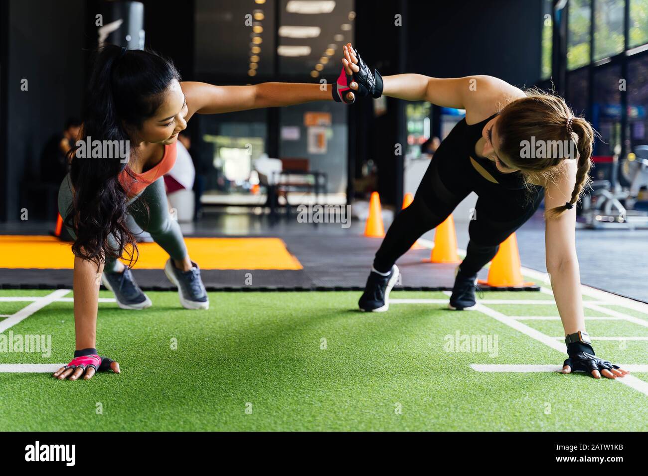 Healthy women giving high five to each other while pushing up in the ...