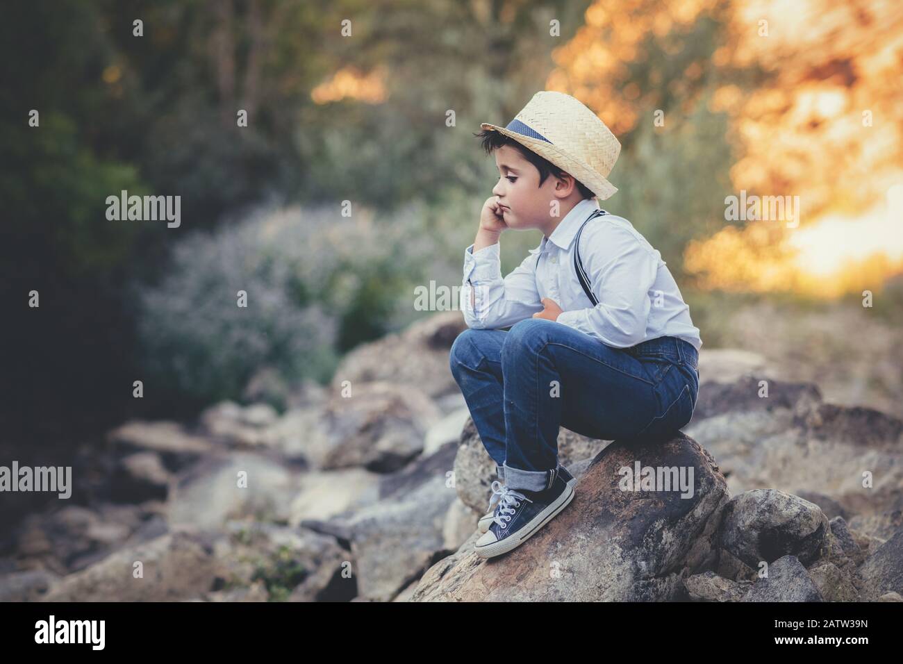 thoughtful child sitting on a rock outdoor Stock Photo - Alamy