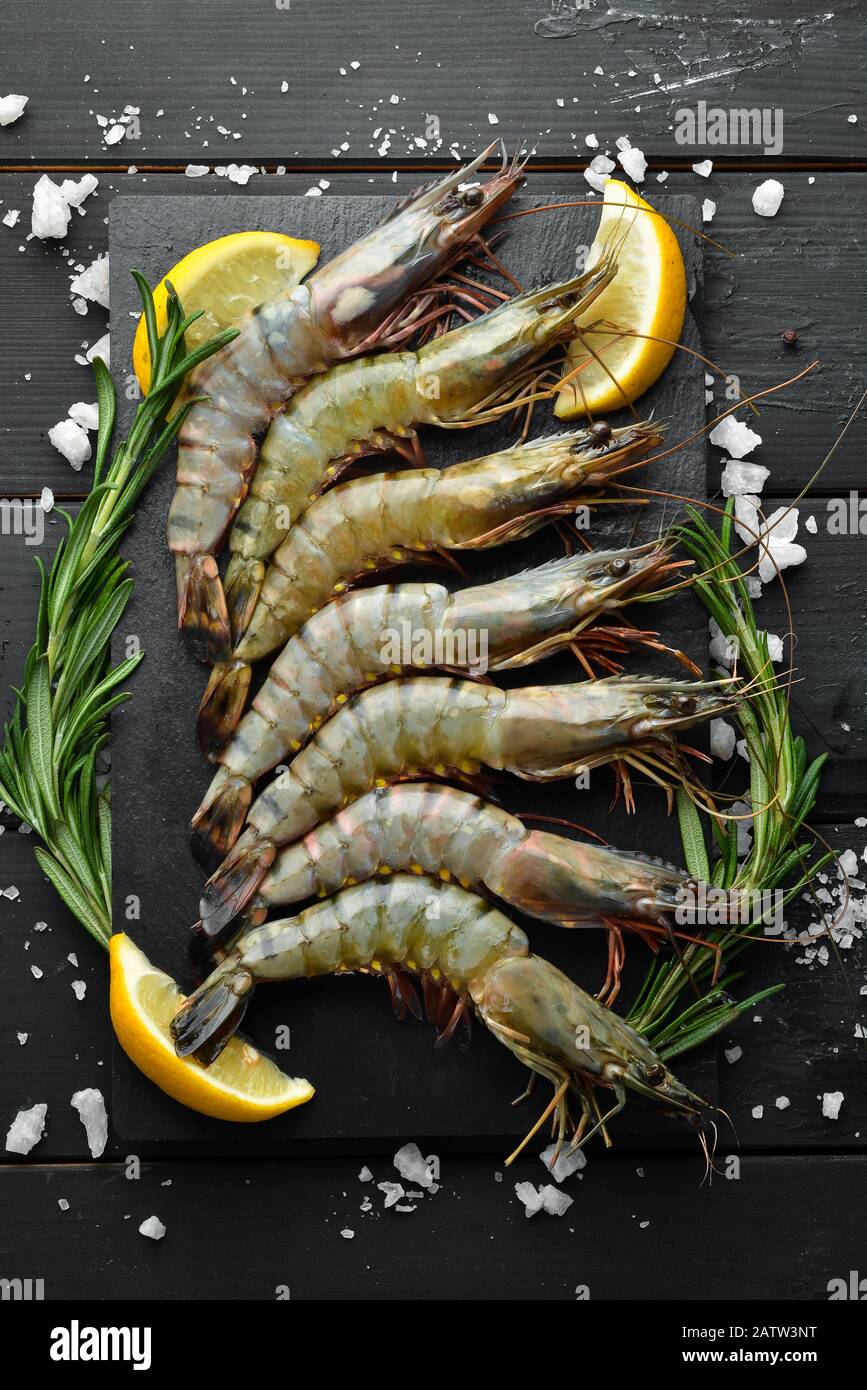 Raw black tiger prawns with lemon. Seafood. Top view. On a black ...