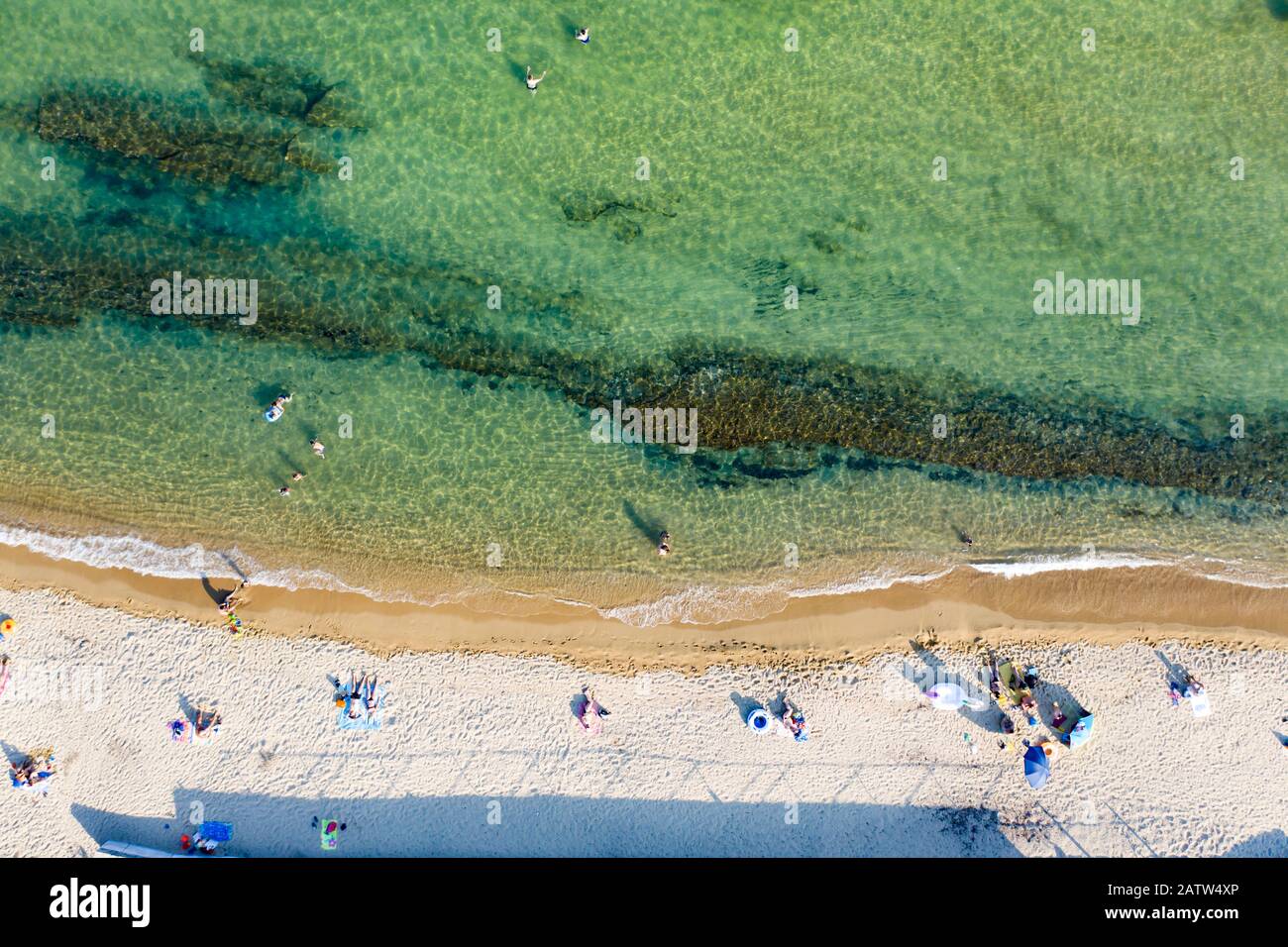 Aerial view of sandy beach with tourists swimming in beautiful clear ...