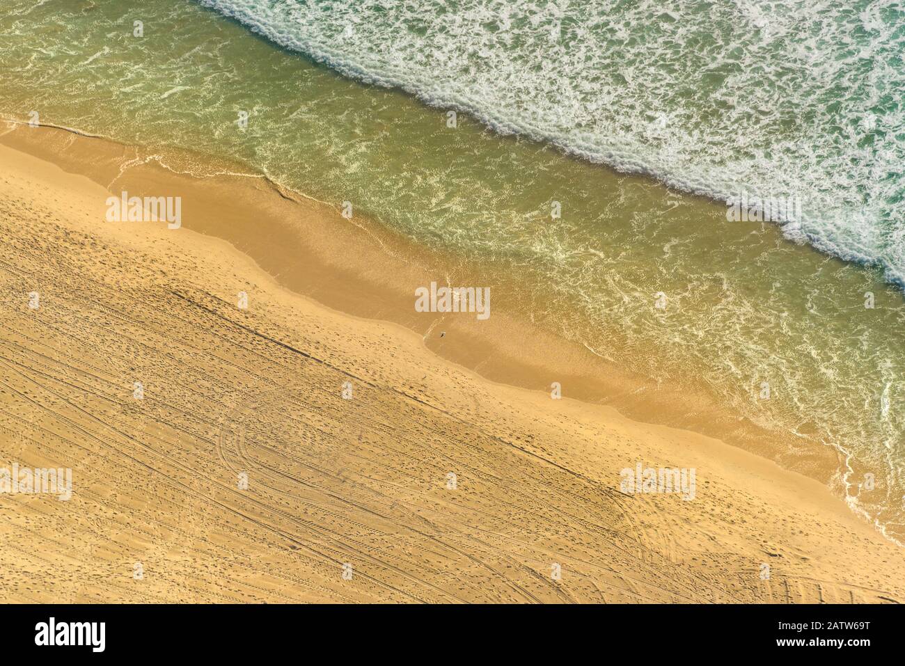 Aerial view of ocean beach with picturesque waves and sunlit sand ...