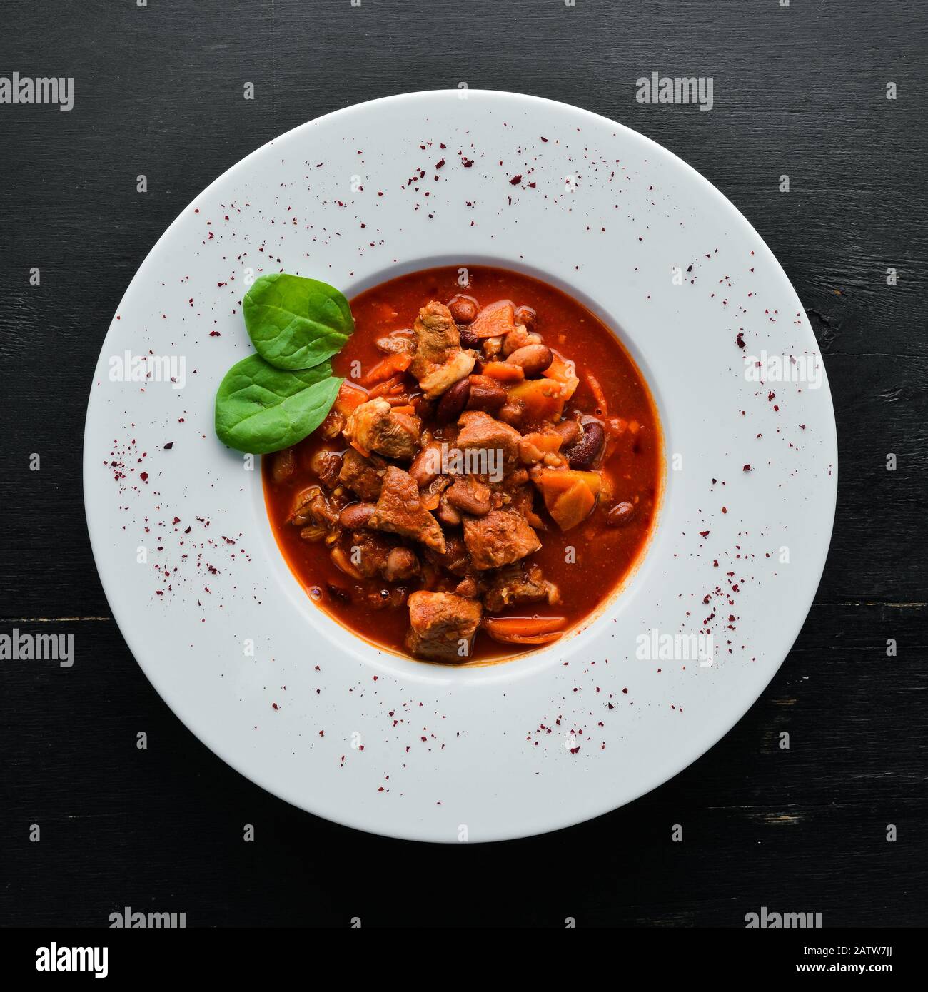 Beef stew with beans and vegetables in a tomato sauce on a plate. Top ...
