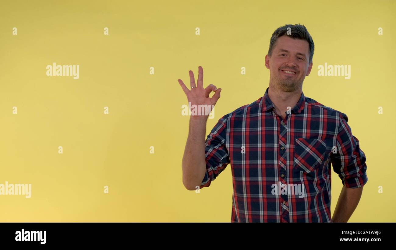 Happy young man making 'okay' hand sign on yellow background. He making ...