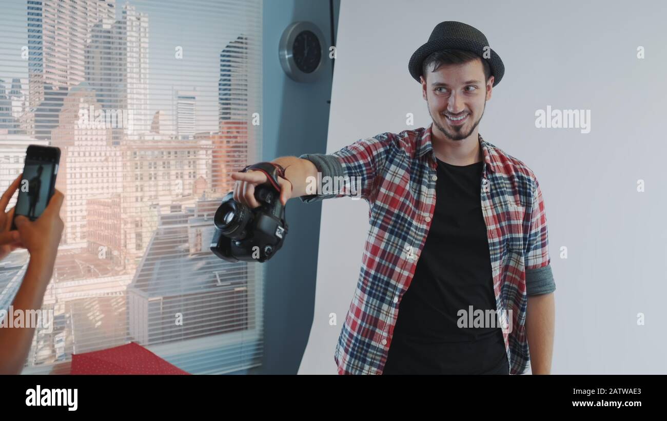 Handsome photographer posing for somebody taking photos with smartphone ...