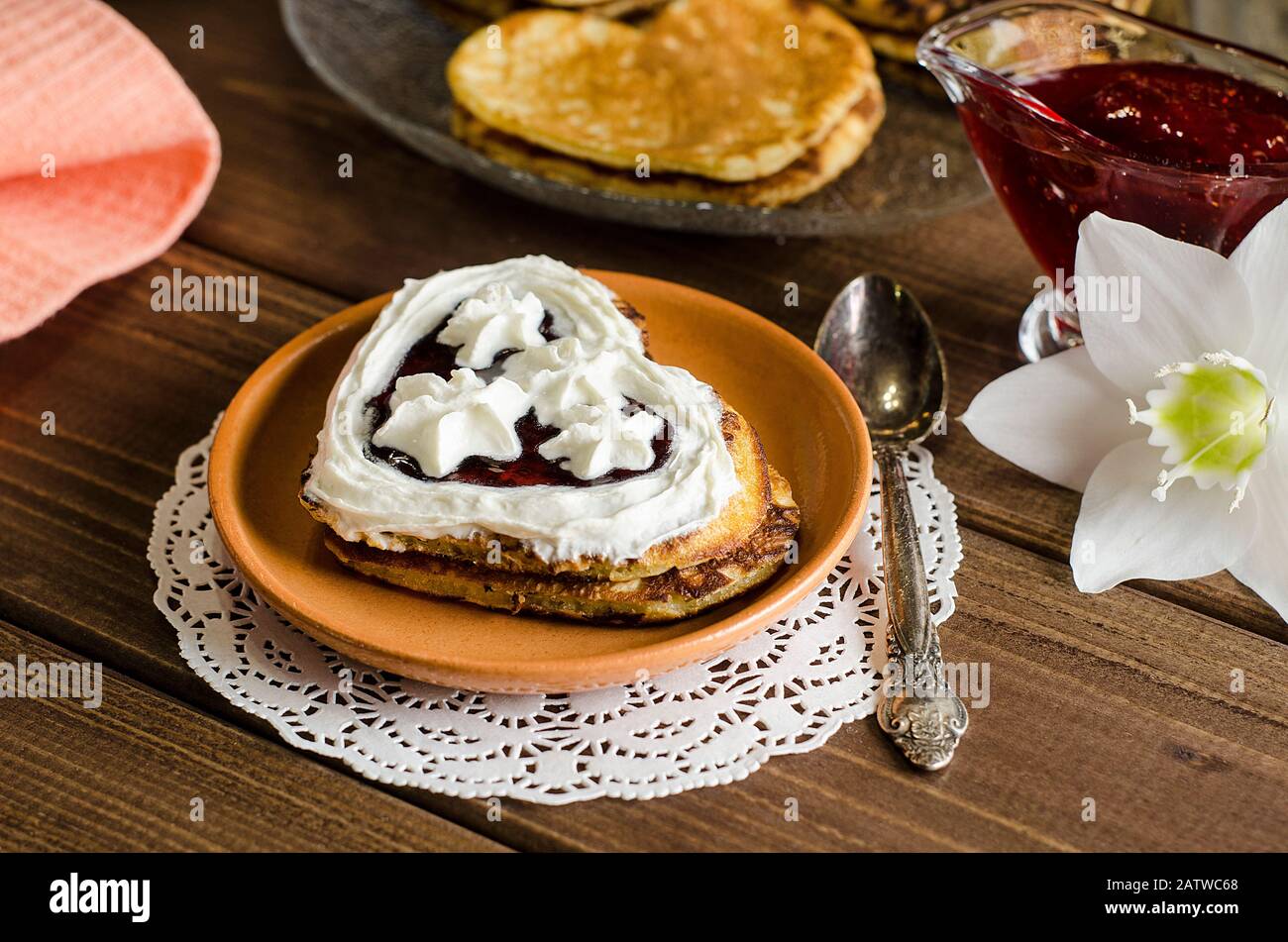Fritters, pancakes in the form of hearts with whipped cream and jam on ...