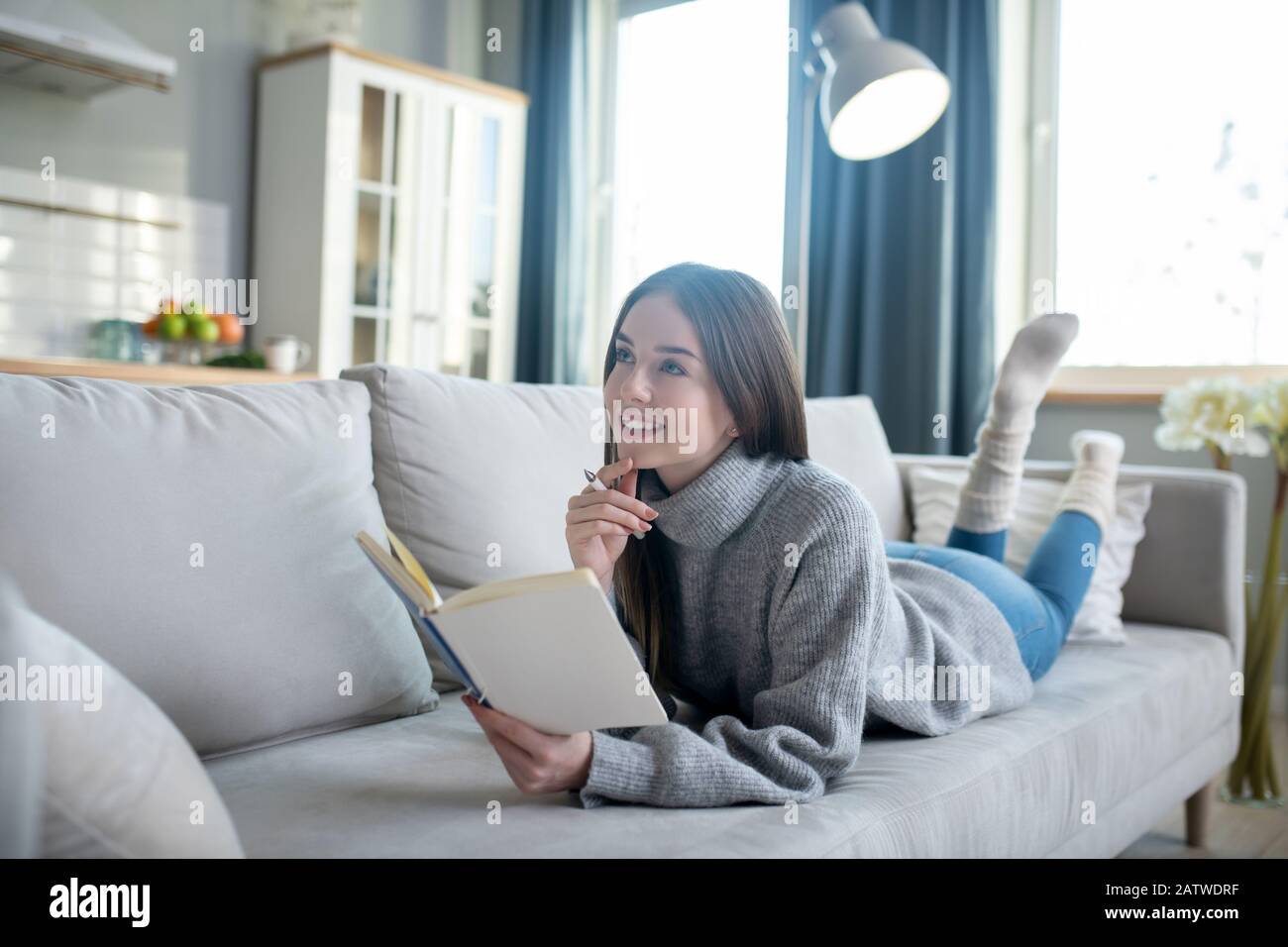 Young girl in a grey sweater thinking over a new idea Stock Photo - Alamy
