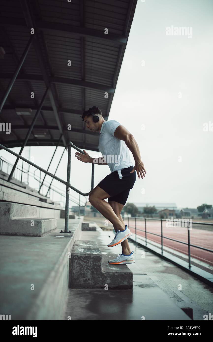 Young muscular man running upstairs on steps at the stadium . Male ...