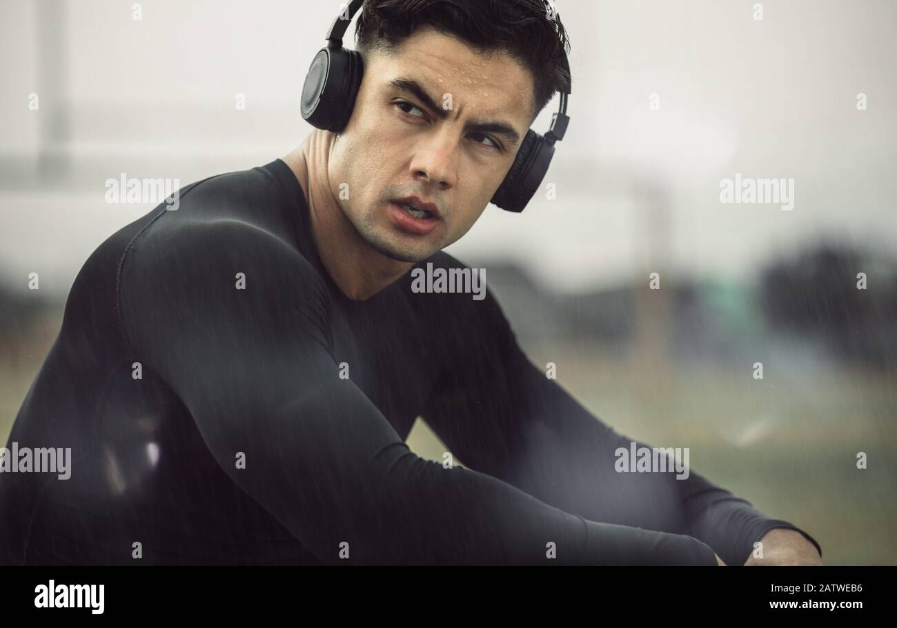 Fit male runner relaxing after workout in rainy morning. Muscular young ...