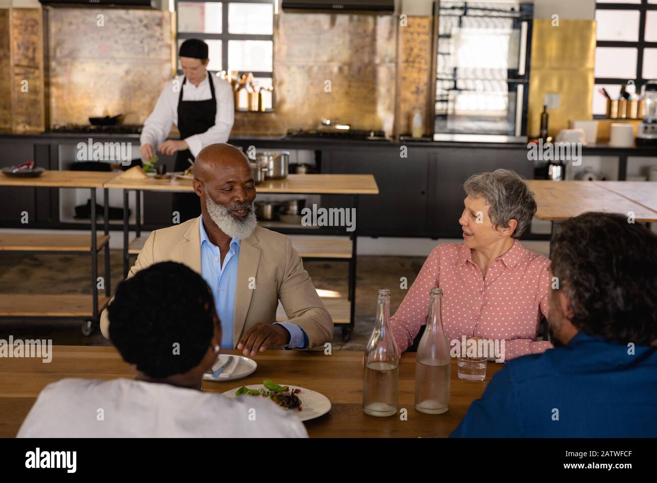 Friends drinking together while cook cooking behind Stock Photo - Alamy