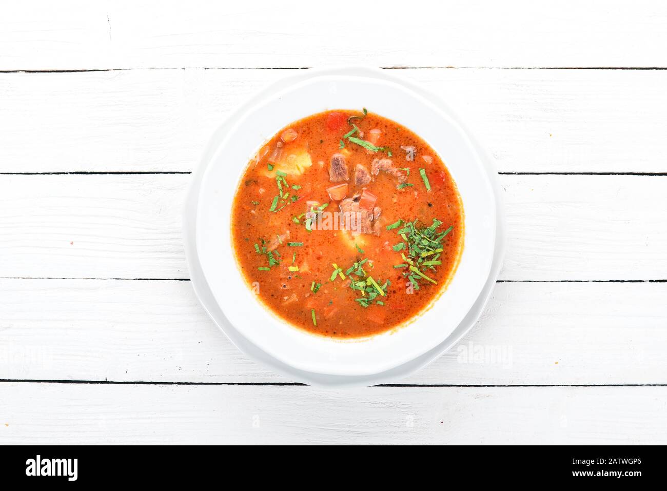 Soup with beef tomatoes and fresh vegetables. On a wooden background ...