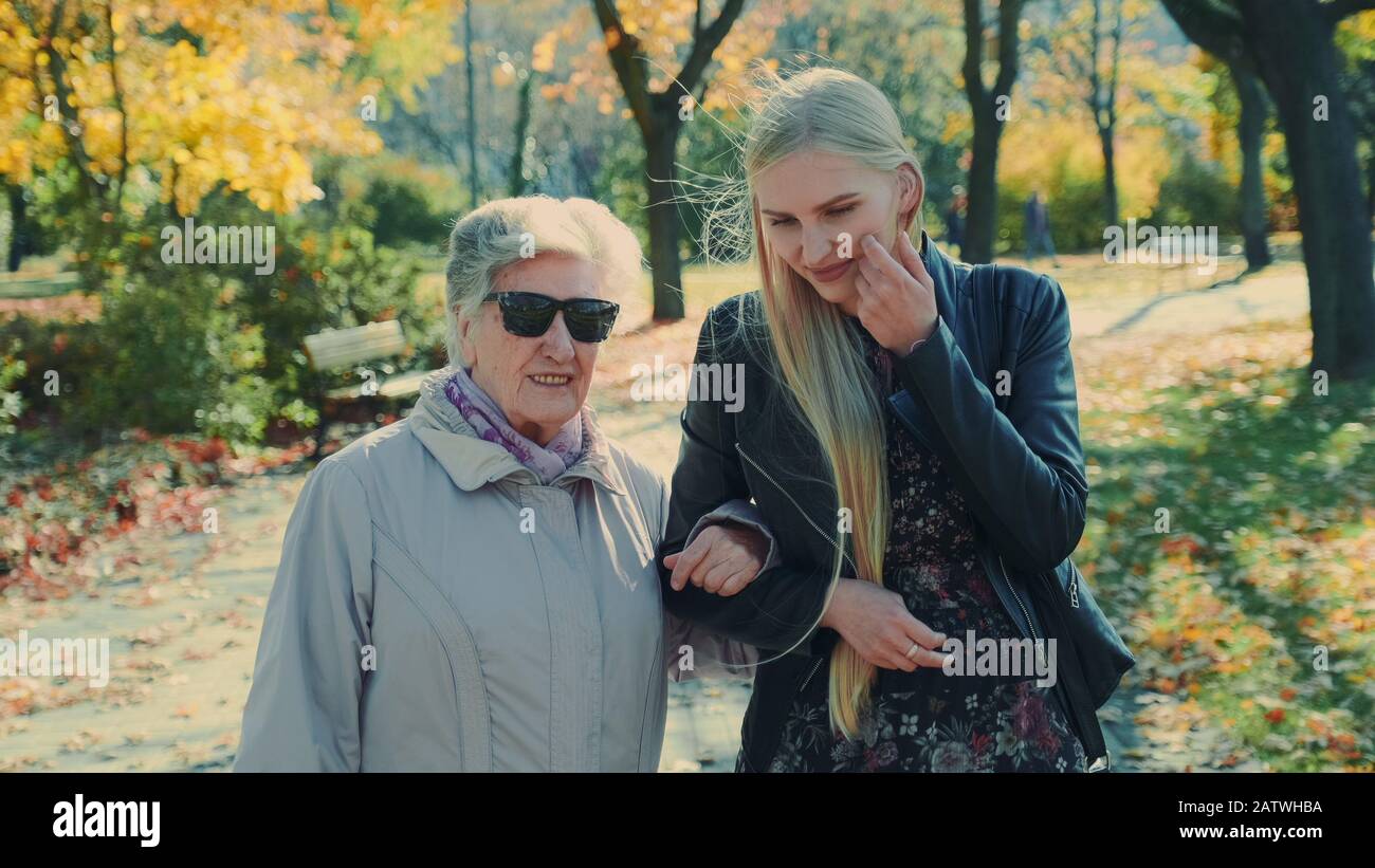 Medium shot of Old woman walking together with cheerful blonde girl in ...