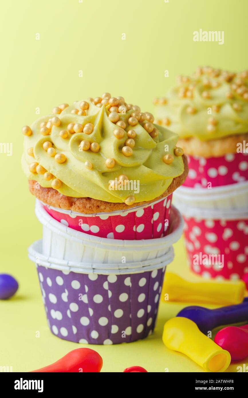 Funny cupcakes in funny polka dot cups and deflated balloons on yellow ...