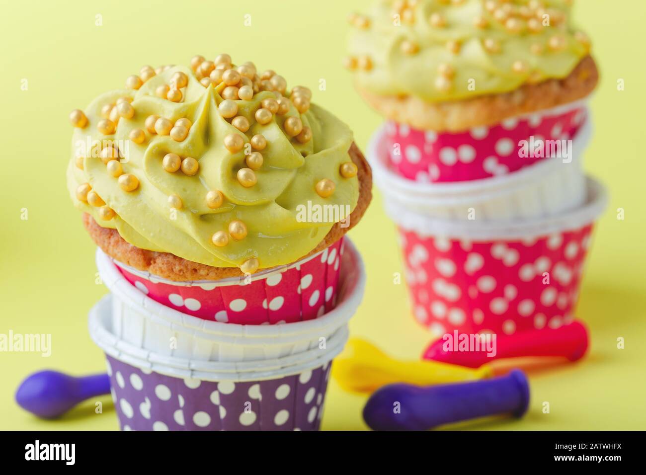 Funny cupcakes in funny polka dot cups and deflated balloons on yellow ...