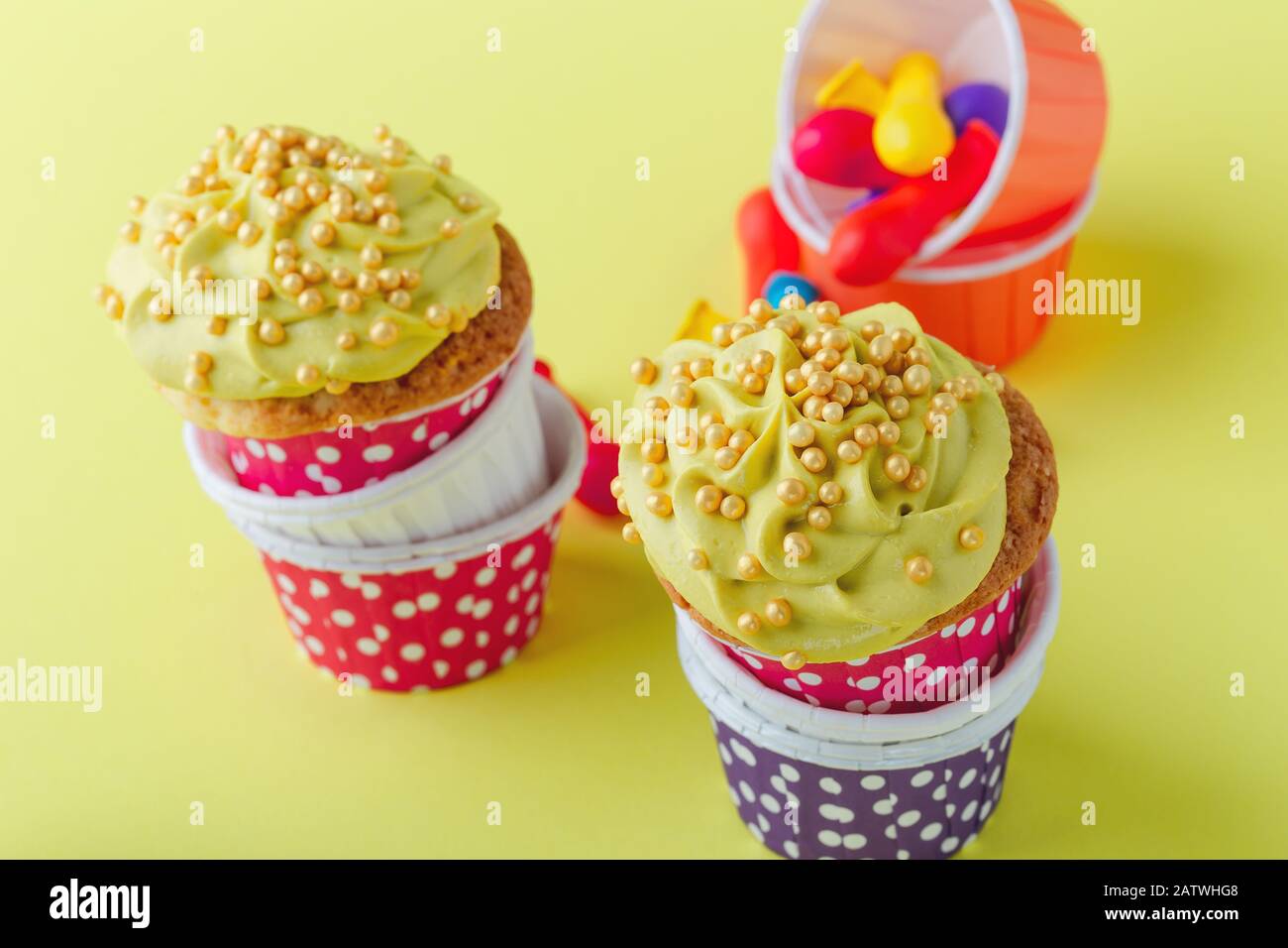 Funny cupcakes in funny polka dot cups and deflated balloons on yellow ...