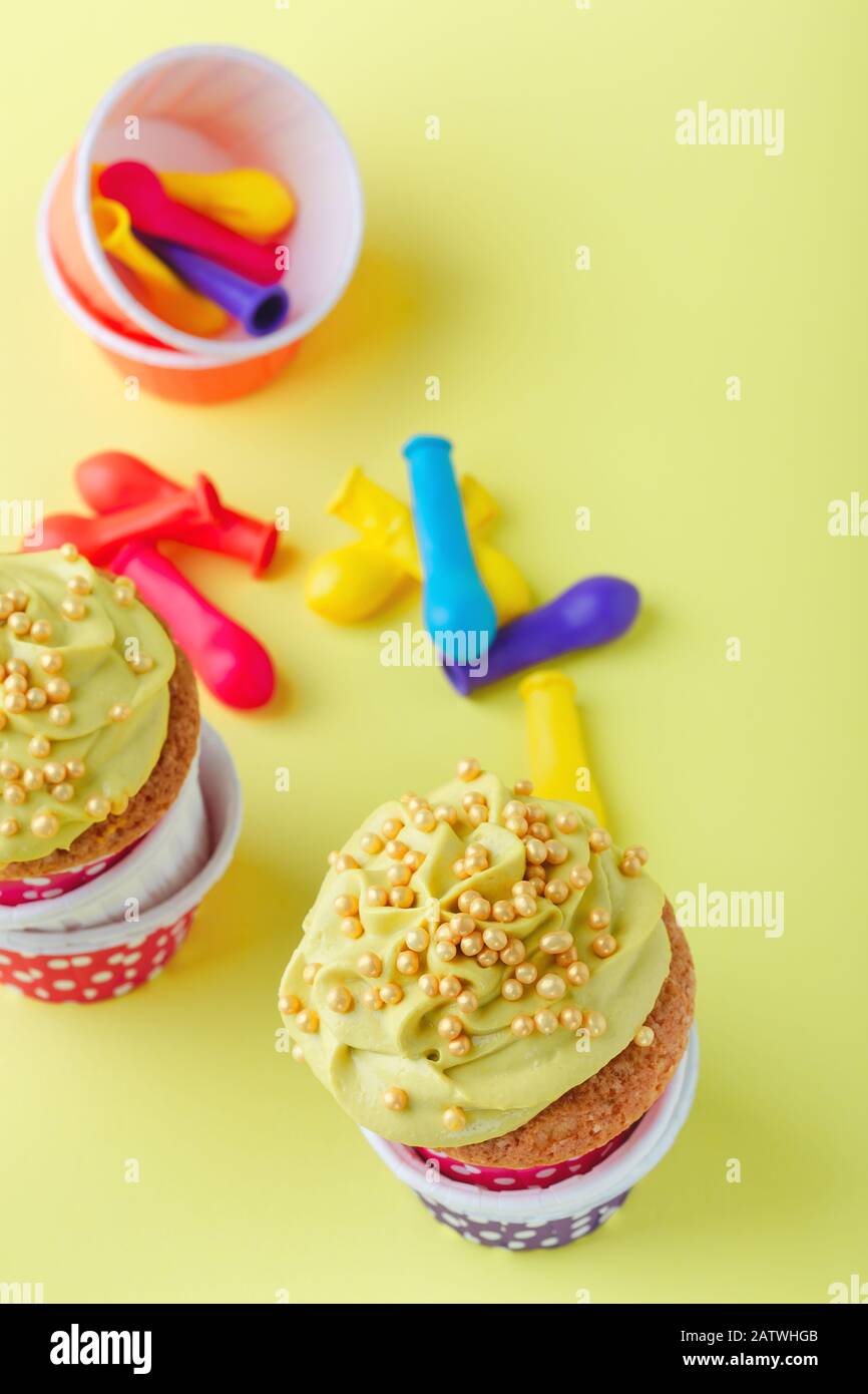Funny cupcakes in funny polka dot cups and deflated balloons on yellow ...