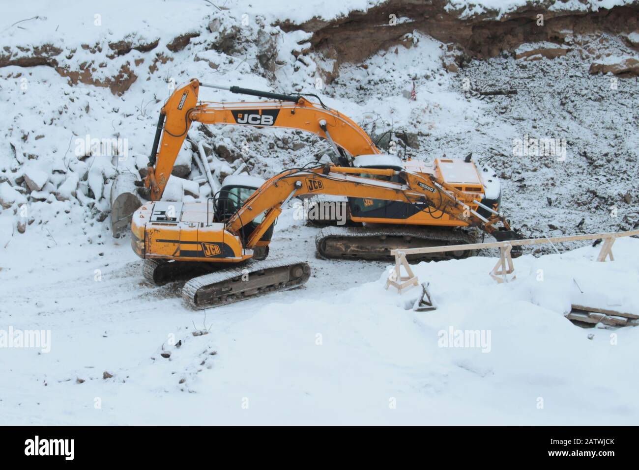 Two yellow crawler excavators dig ground in the pit in winter. Heavy ...
