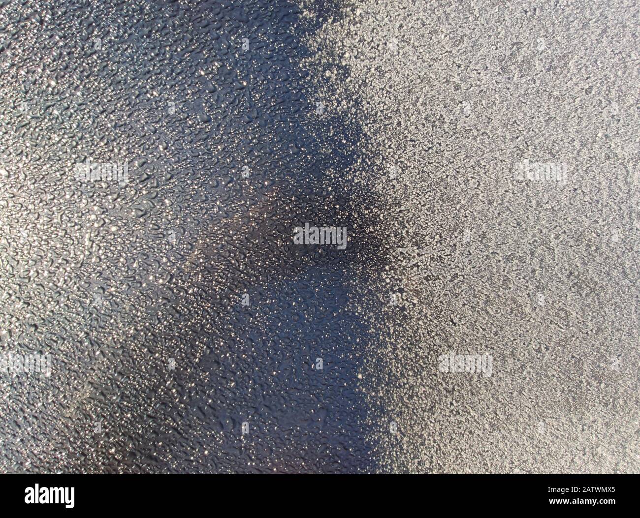 Frozen texture covered by a thin layer of snow. The sun shines and ...