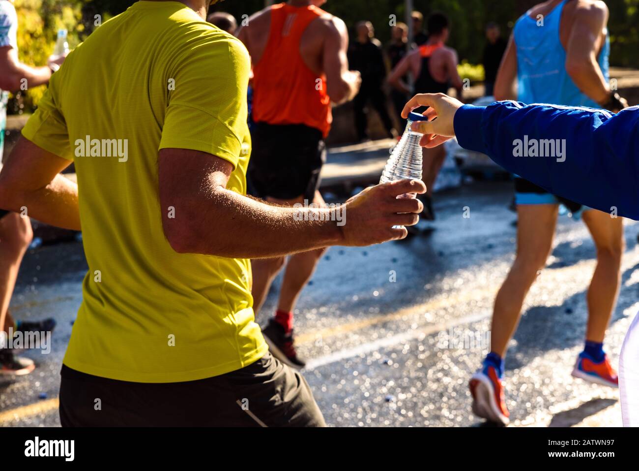 A helping hand delivers a bottle of water to a runner in a running race ...