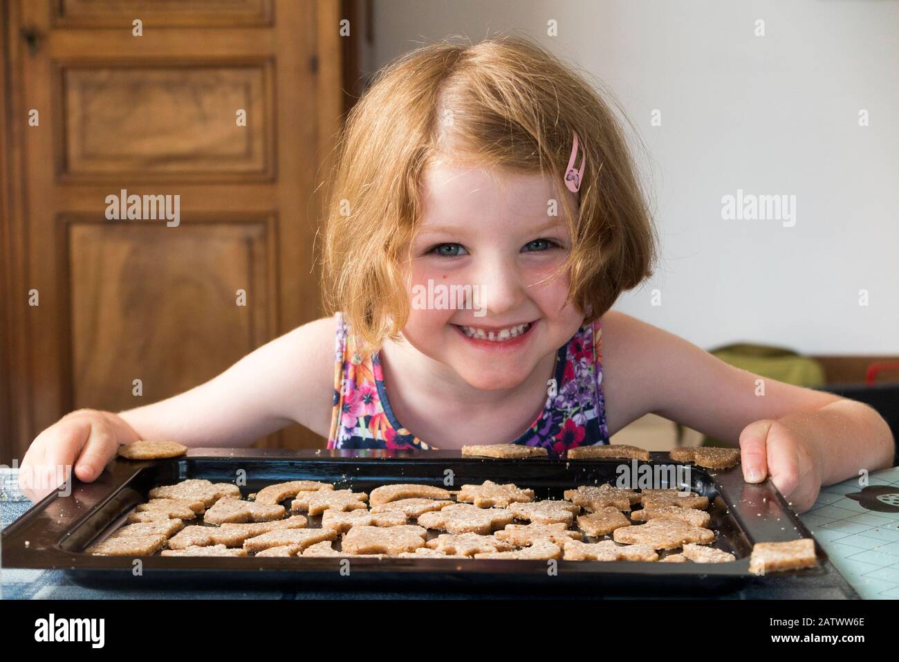 Girl aged 5 / five years using a pastry cutter while baking biscuit ...